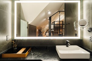 Um banheiro moderno com um espelho grande, uma pia branca e um mueble de madeira.