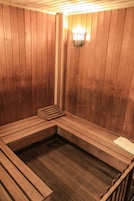 Uma sauna de madeira com bancos e um candeeiro fixado na parede.