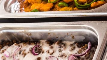 Buffet com diversos pratos, incluindo frituras e um prato cremoso de lentilha.