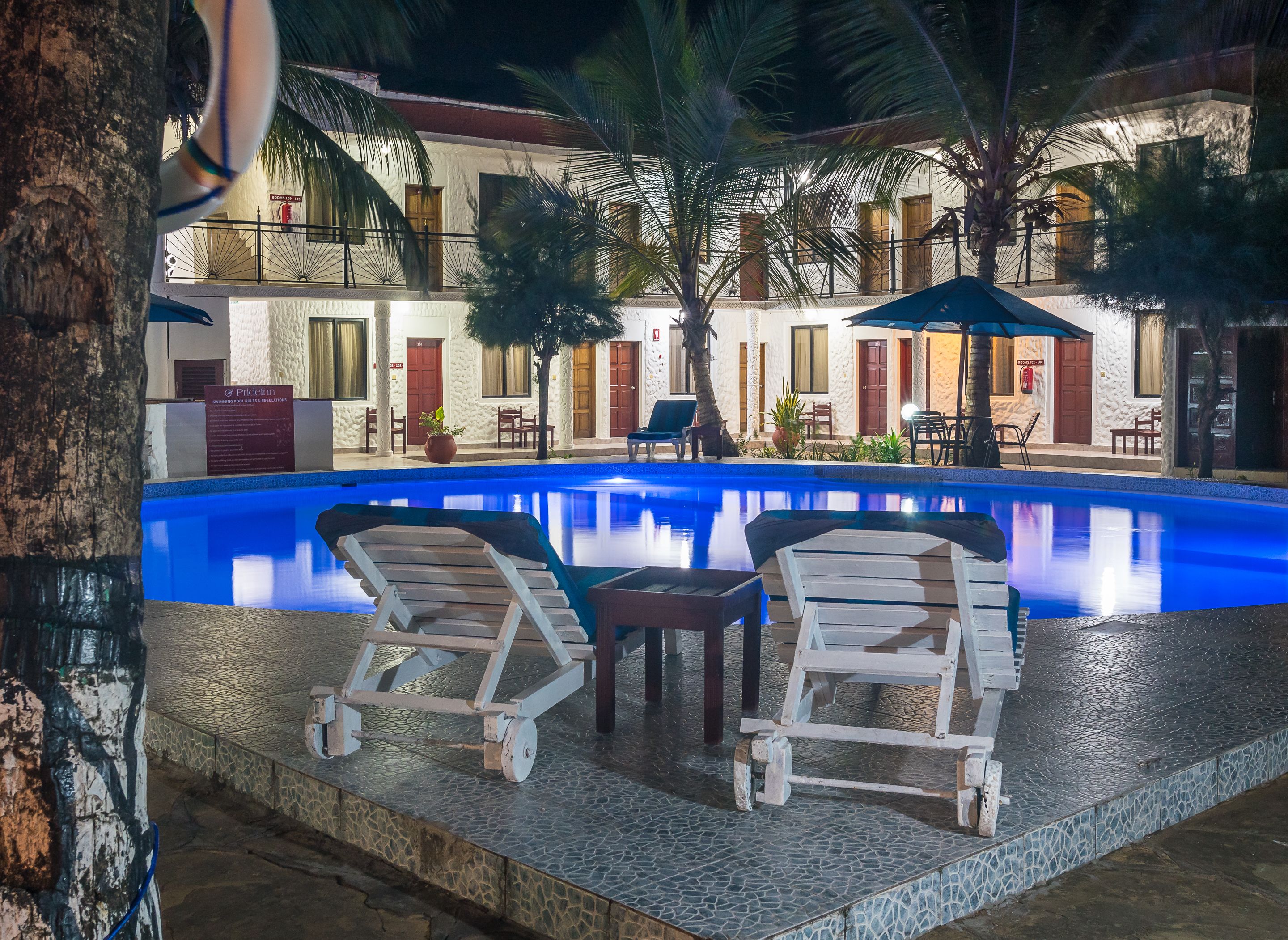 Uma área de piscina com espreguiçadeiras e uma placa com o texto 'Pradeinn'.