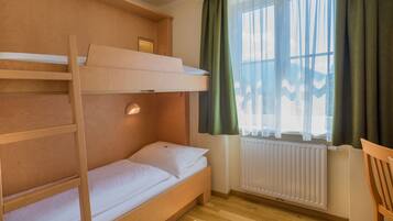 Quarto com beliche, janela, cortinas e radiador.