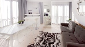 Uma sala de estar moderna com um tapete de zebra, um sofá cinza e uma mesa de jantar branca com cadeiras.