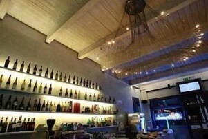 Um bar com prateleiras cheias de garrafas e um teto com design original.