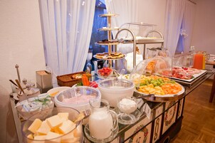 Buffet com diversos alimentos e bebidas, incluindo frutas, queijos e um jarro de leite.