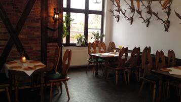 Uma sala de jantar com paredes de tijolo, cadeiras de madeira e uma mesa posta para dois.