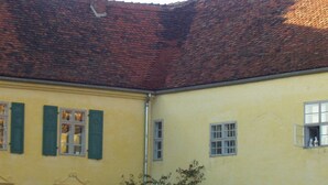 Um edifício amarelo com portanelas verdes e telhado de azulejos.