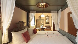 Quarto de hotel com duas camas, roupa de cama branca, cabeceira de madeira, uma pequena mesa com abajur e um espelho na parede.