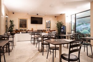 Restaurante moderno com piso de mármore, cadeiras pretas e espaço para buffet.