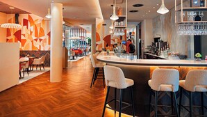 Uma área de bar moderna com balcão curvo, banquetas e um bartender.