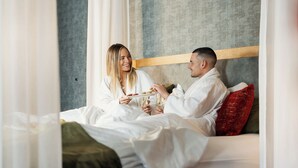 Um casal em quarto de hotel, com cama, almofadas e cabeceira.