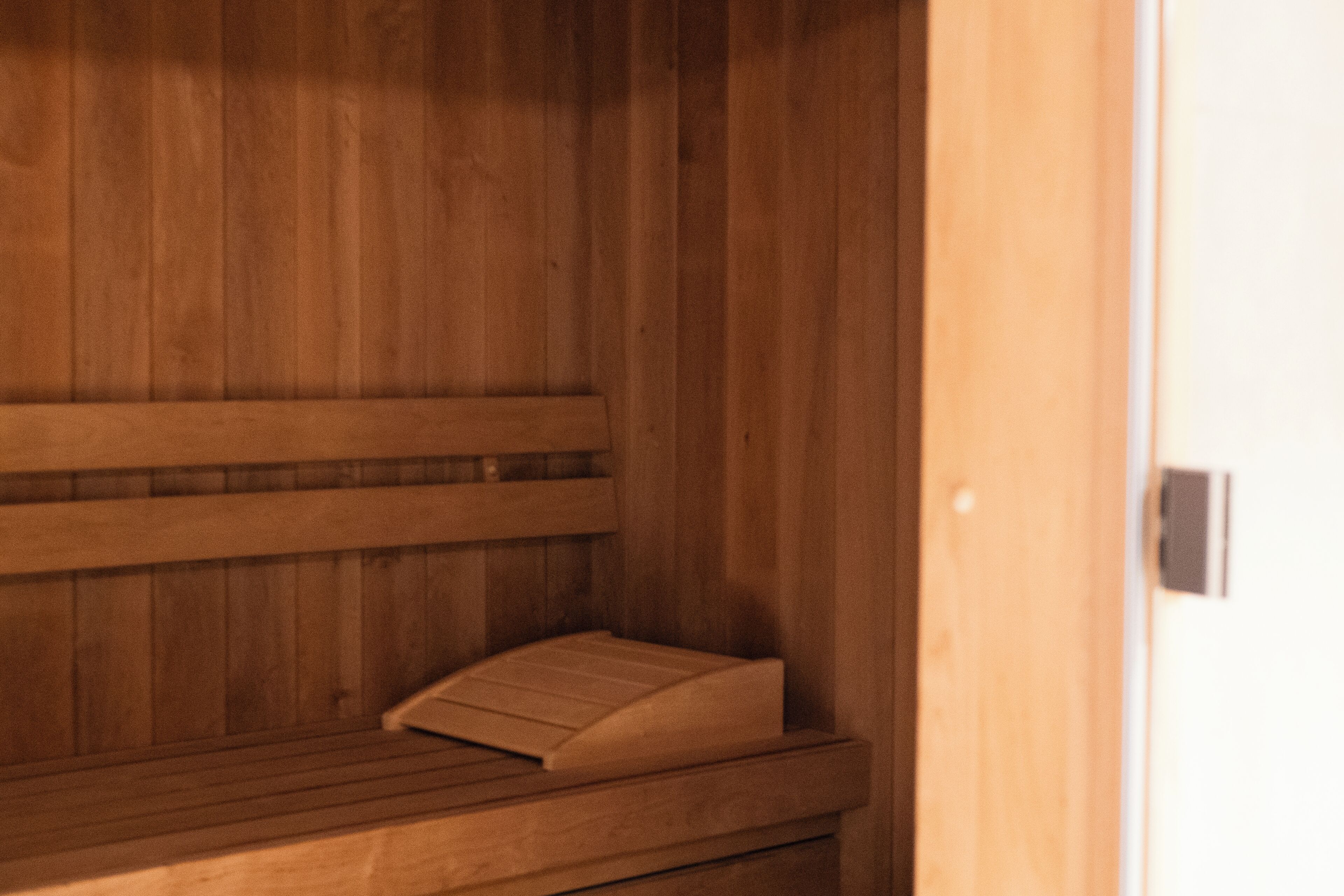 Uma sauna de madeira com bancos e assento.
