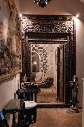 Uma porta ornamentada dá acesso a uma sala de estar com um sofá e uma mesa de jantar com cadeiras.