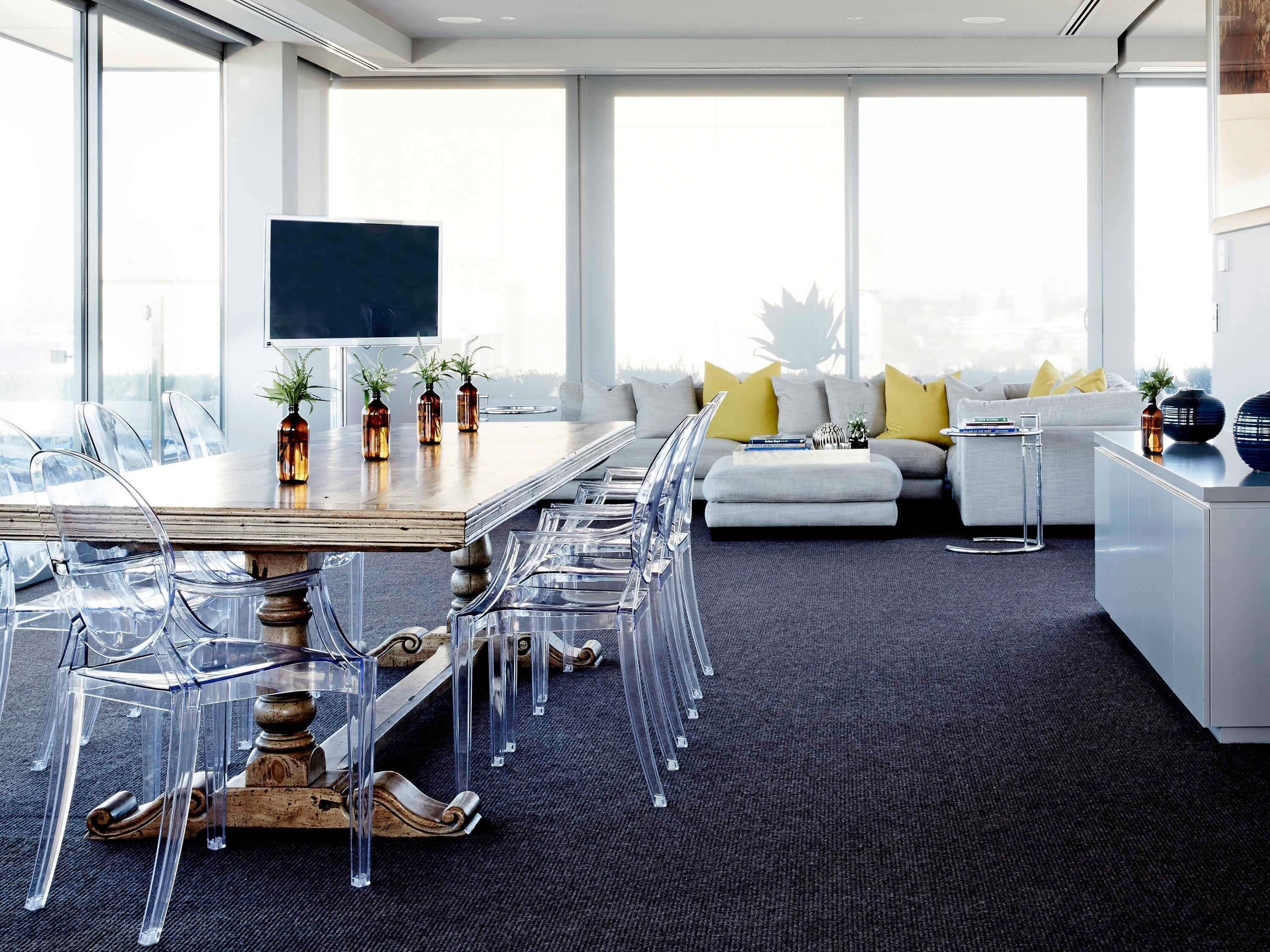 Uma sala de reuniões moderna com uma mesa grande, cadeiras confortáveis, um sofá e uma TV.