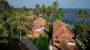 Resort costeiro com vários edifícios no estilo de bungalows, palmeiras e vista para o oceano.