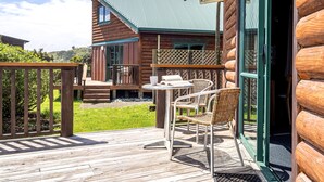 Uma cabana de madeira com um deck, área de estar externa e vista para a paisagem ao redor.