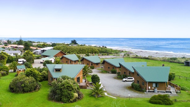 Um resort costeiro com várias cabanas de madeira, uma praia e vista clara do oceano.
