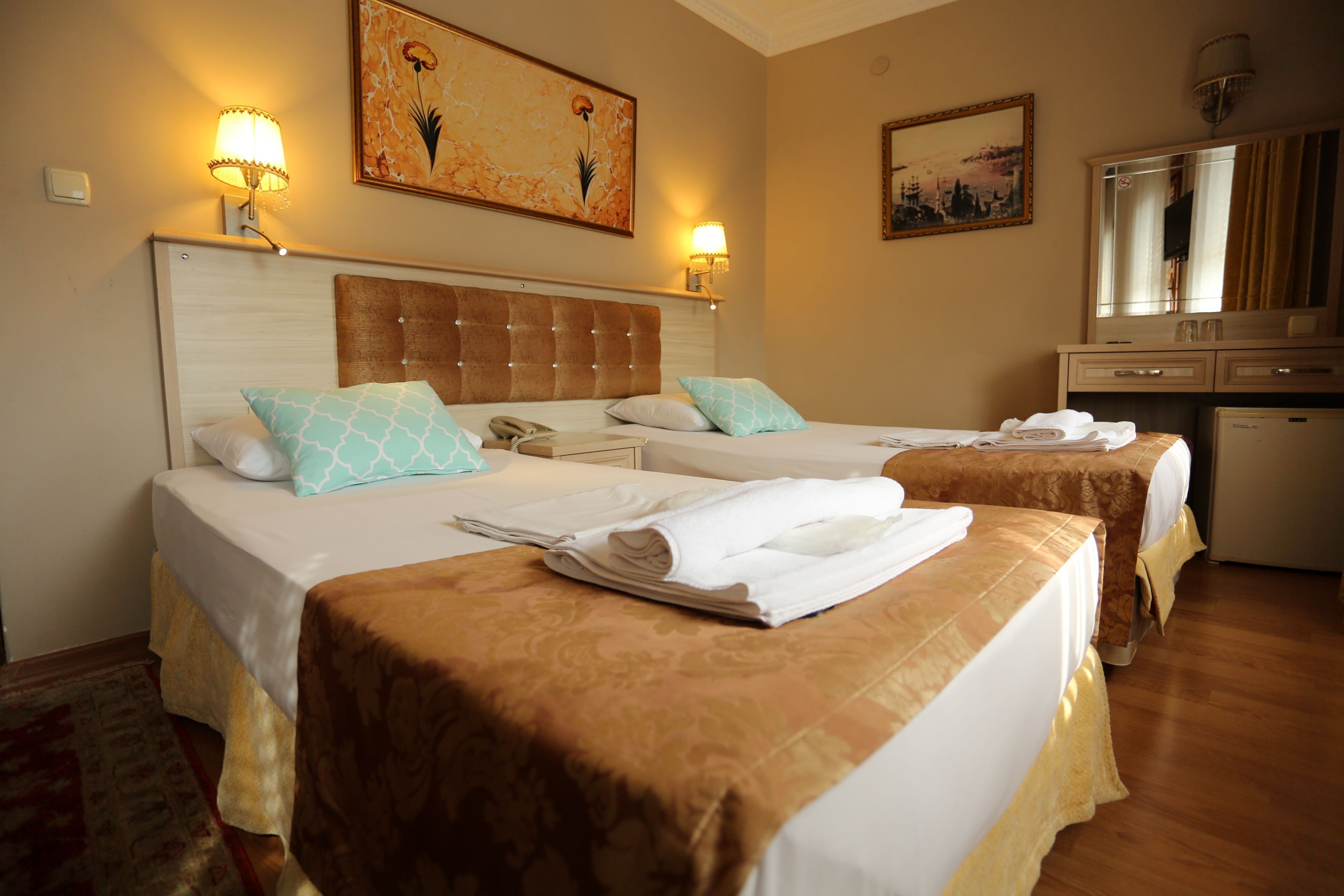 Quarto de hotel com duas camas, uma escrivaninha e um espelho.