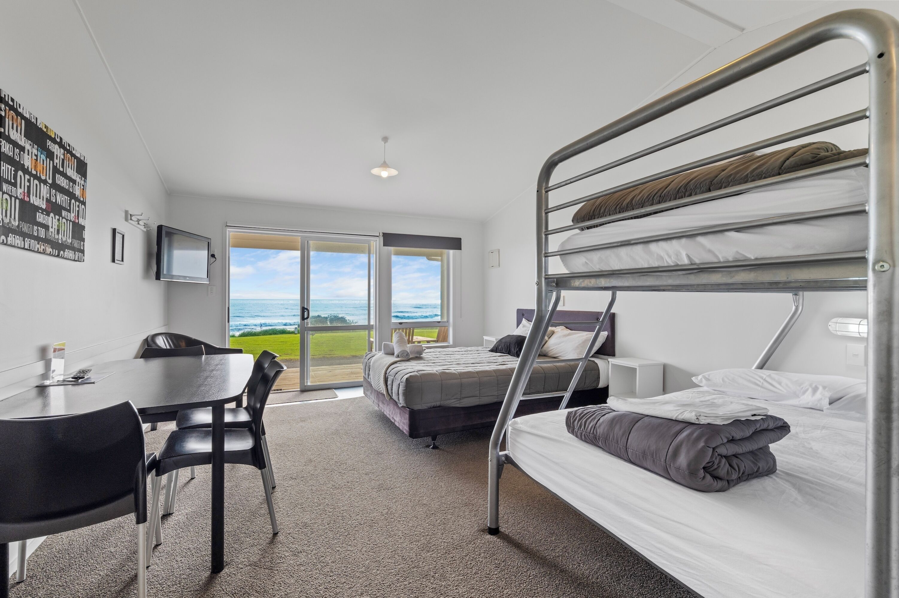 Quarto moderno com beliche, escrivaninha e cadeira. Grande janela com vista para o oceano.