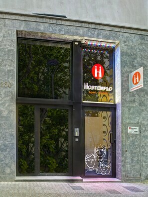 Entrada de hotel com uma grande porta de vidro, uma placa Hostempolo e o número de quarto 280 visível.