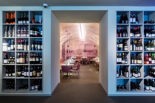 Uma adega com prateleiras cheias de garrafas de vinho e um espaço de refeições com mesas e cadeiras.