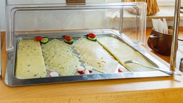 Buffet com diversos queijos, rabanetes e pepinos.