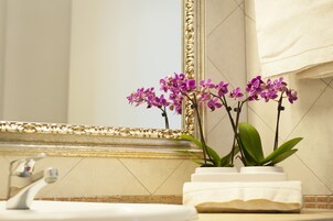 Casa de banho com lavatório, espelho e duas orquídeas em vasos.