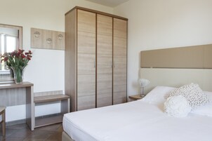 Quarto com cama, mesa de cabeceira, criado-mudo e guarda-roupa.