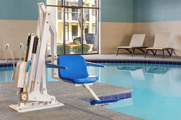 Área da piscina com uma cadeira azul, elevador de piscina e espreguiçadeira.