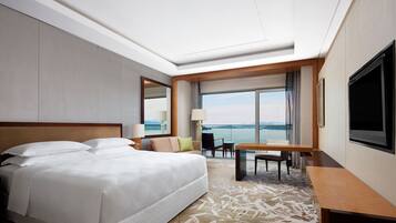 Quarto de hotel com uma cama grande, área de refeições e vista para o mar.
