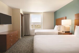 Quarto de hotel com duas camas, televisão, secretária e janela com vista.