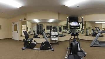 Academia com diversos equipamentos de exercício, incluindo esteiras, bicicletas ergométricas e aparelhos de musculação.