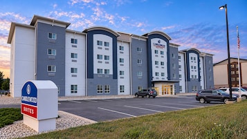 Um hotel com vários andares, um estacionamento e uma placa indicando 'Candlewood Suites'.