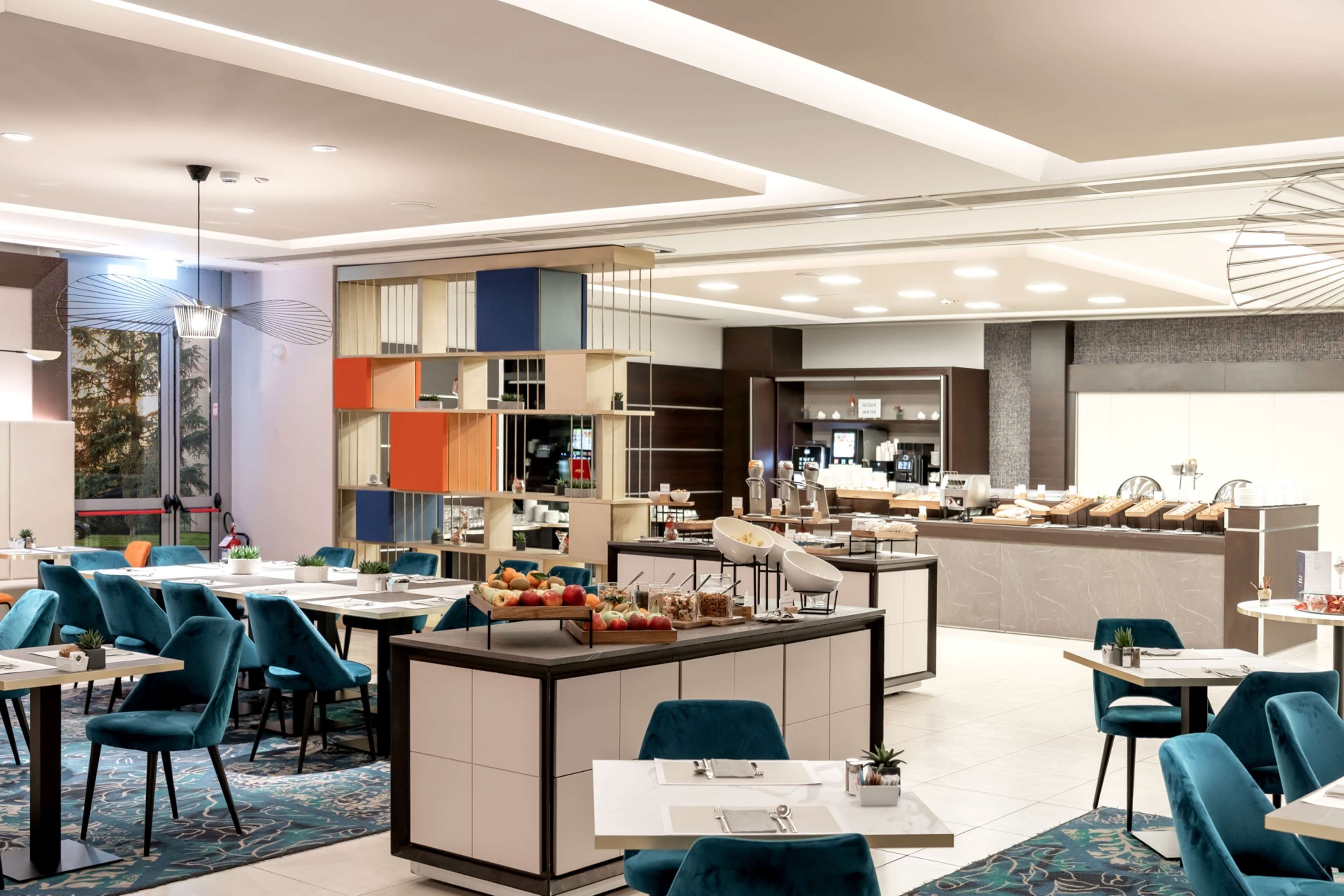 Um hall de hotel moderno com uma ilha central, áreas de estar e um balcão de recepção.