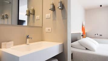 Uma casa de banho moderna com uma grande pia, espelho e artigos de higiene pessoal fixados na parede.