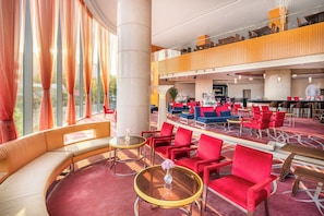 Um saguão de hotel com área de estar, balcão de recepção e bar.