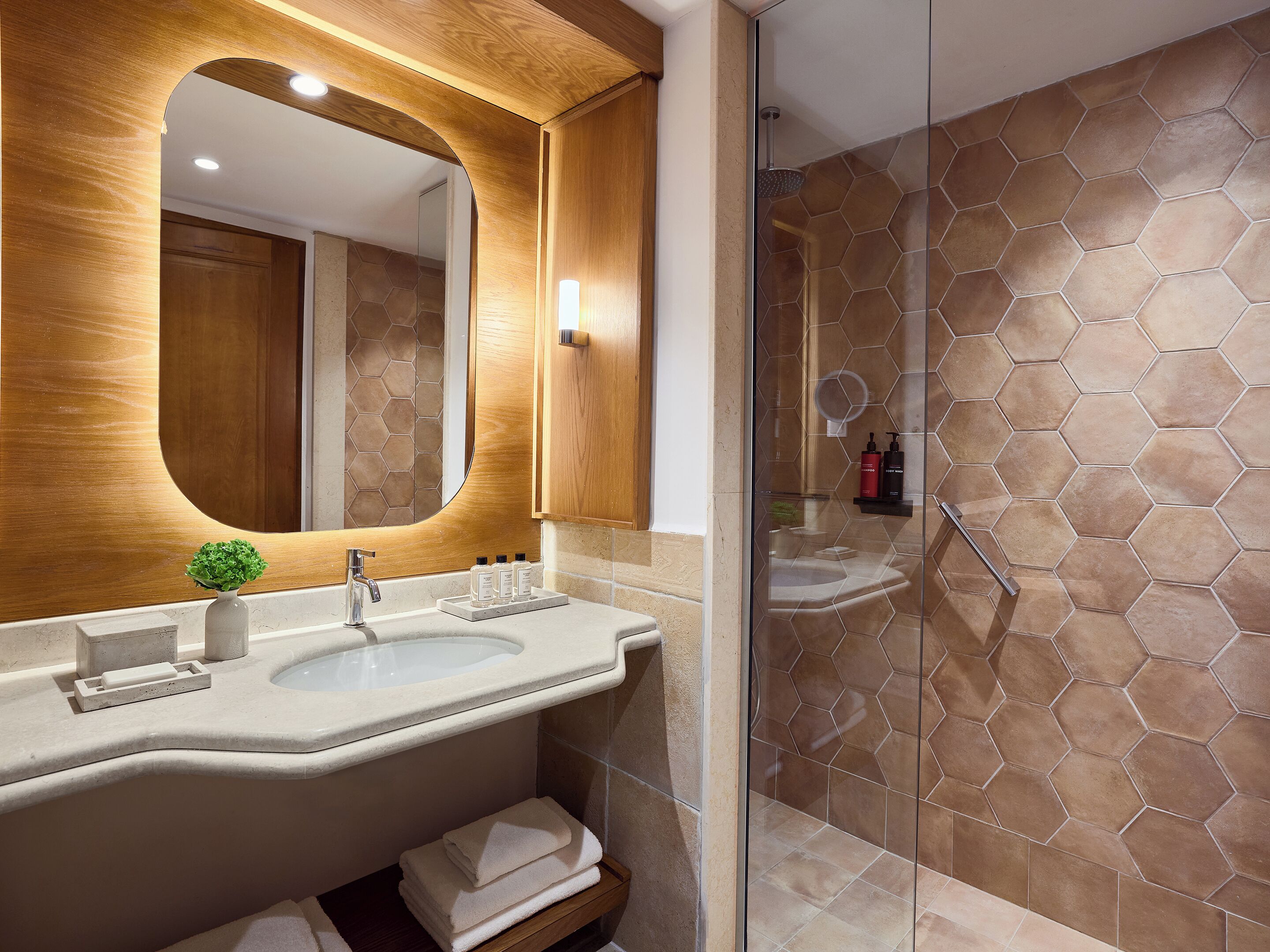 Casa de banho moderna com duas pias, um espelho grande e zona de duche com azulejos hexagonais.