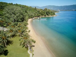 Uma praia com águas cristalinas, palmeiras e um píer.