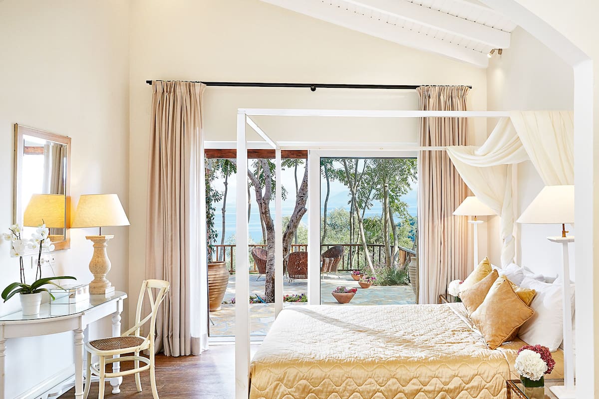 Quarto com uma cama grande, uma escrivaninha com cadeira e vista para o exterior.
