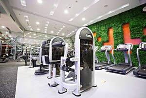 Uma academia moderna com diversos equipamentos de exercício, uma parede verde e um espelho grande.