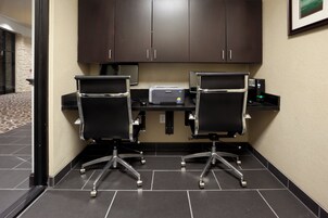 Sala de conferências com duas cadeiras de escritório pretas, um computador de mesa e uma impressora.