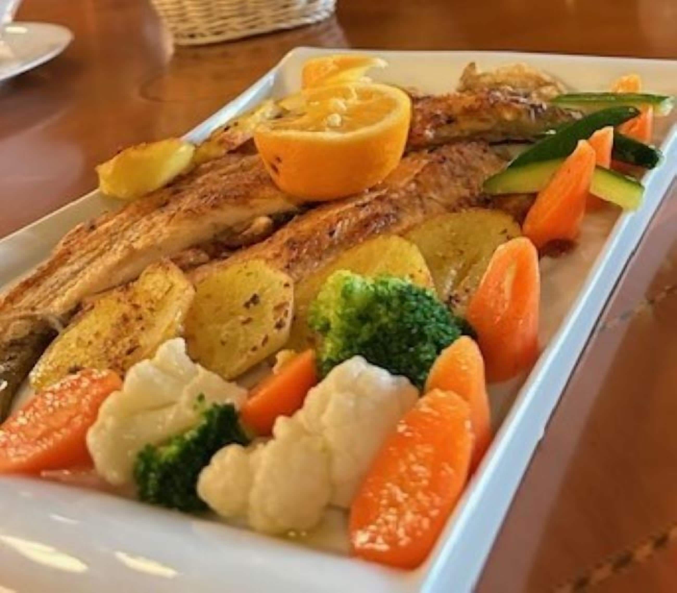 Prato de peixe grelhado com batatas, cenouras, brócolis e couve-flor assados.