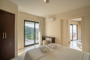 Quarto de hotel com uma cama grande, uma escrivaninha e vista para uma varanda.