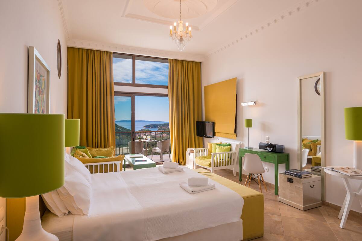 Quarto de hotel com cama, escrivaninha, cadeira e vista para o exterior.