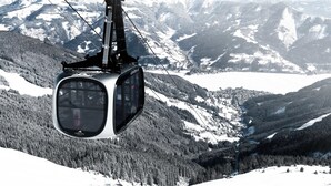 Um teleférico oferece vista clara de montanhas cobertas de neve e um vale abaixo.