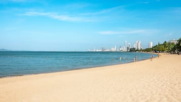 Na praia, areia branca, guarda-sóis, toalhas de praia