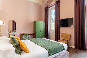 Um quarto com uma cama, um guarda-roupa verde, uma televisão e uma janela com cortinas.