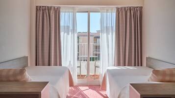 Quarto de hotel com duas camas, varanda e vista para edifícios.
