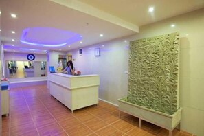 Uma área de recepção com balcão, parede decorativa e piso revestido de azulejos.