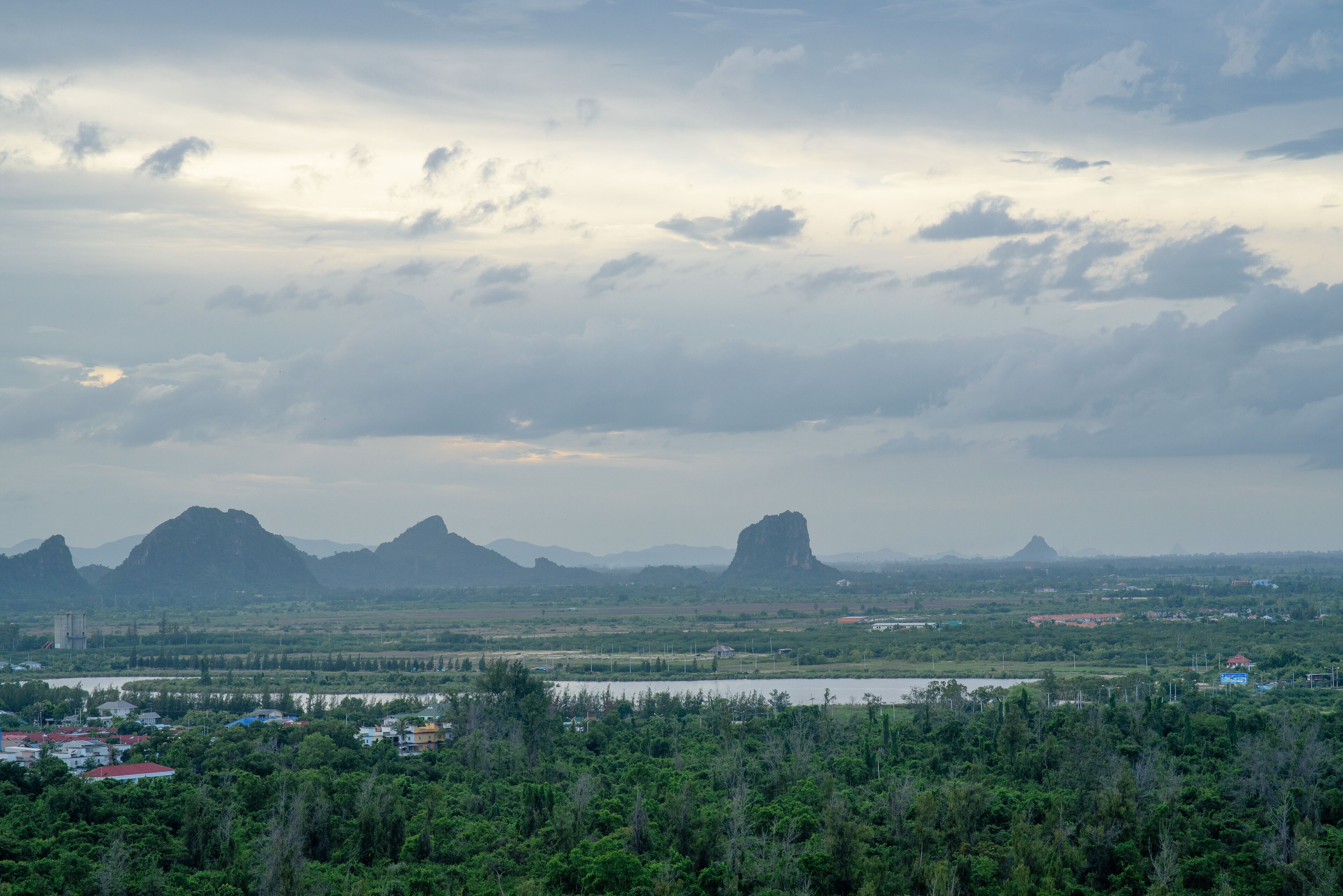 Vista panorâmica de uma paisagem com montanhas, um rio e algumas construções espalhadas.