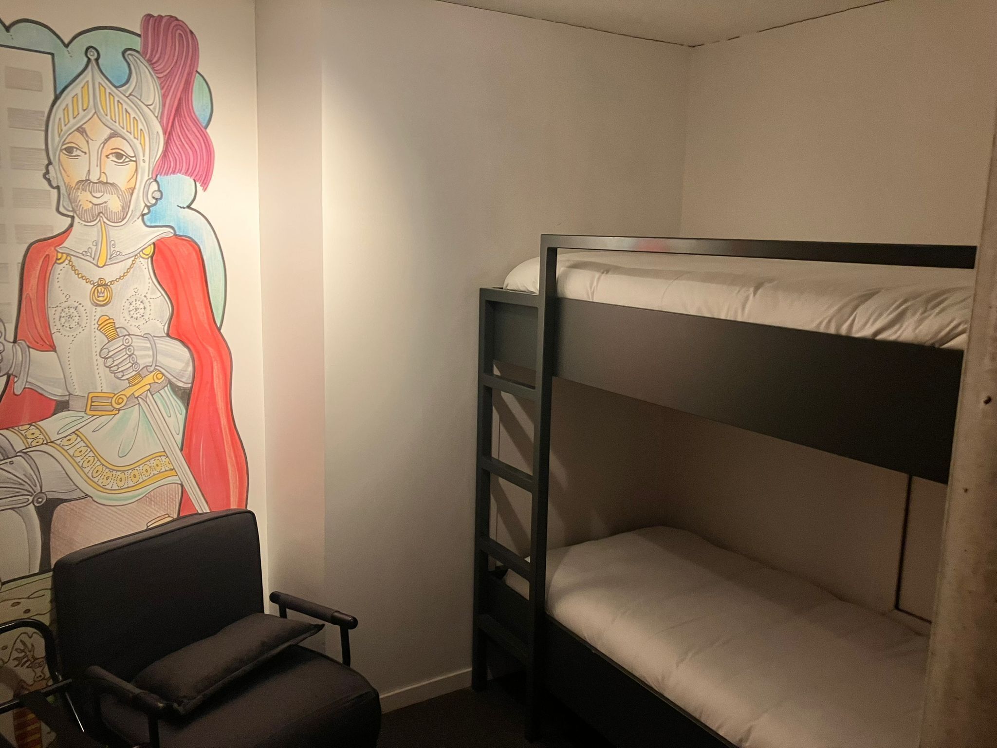 Quarto com beliche e um mural na parede.